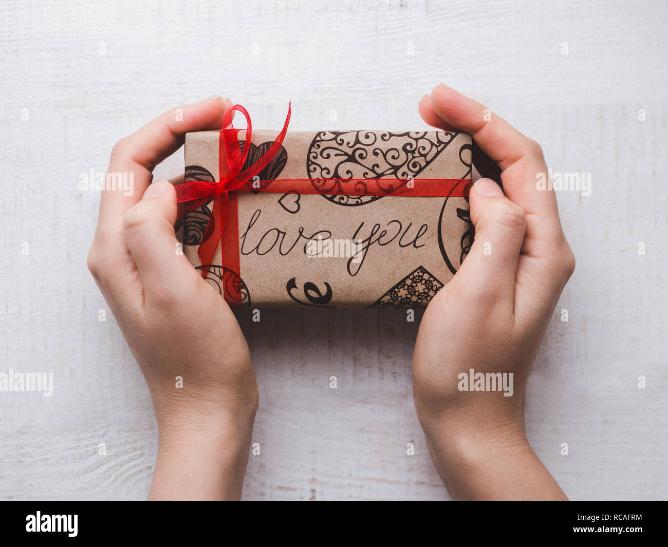 Hands holding a box with a gift, tied by a ribbon, on a white, isolated ...
