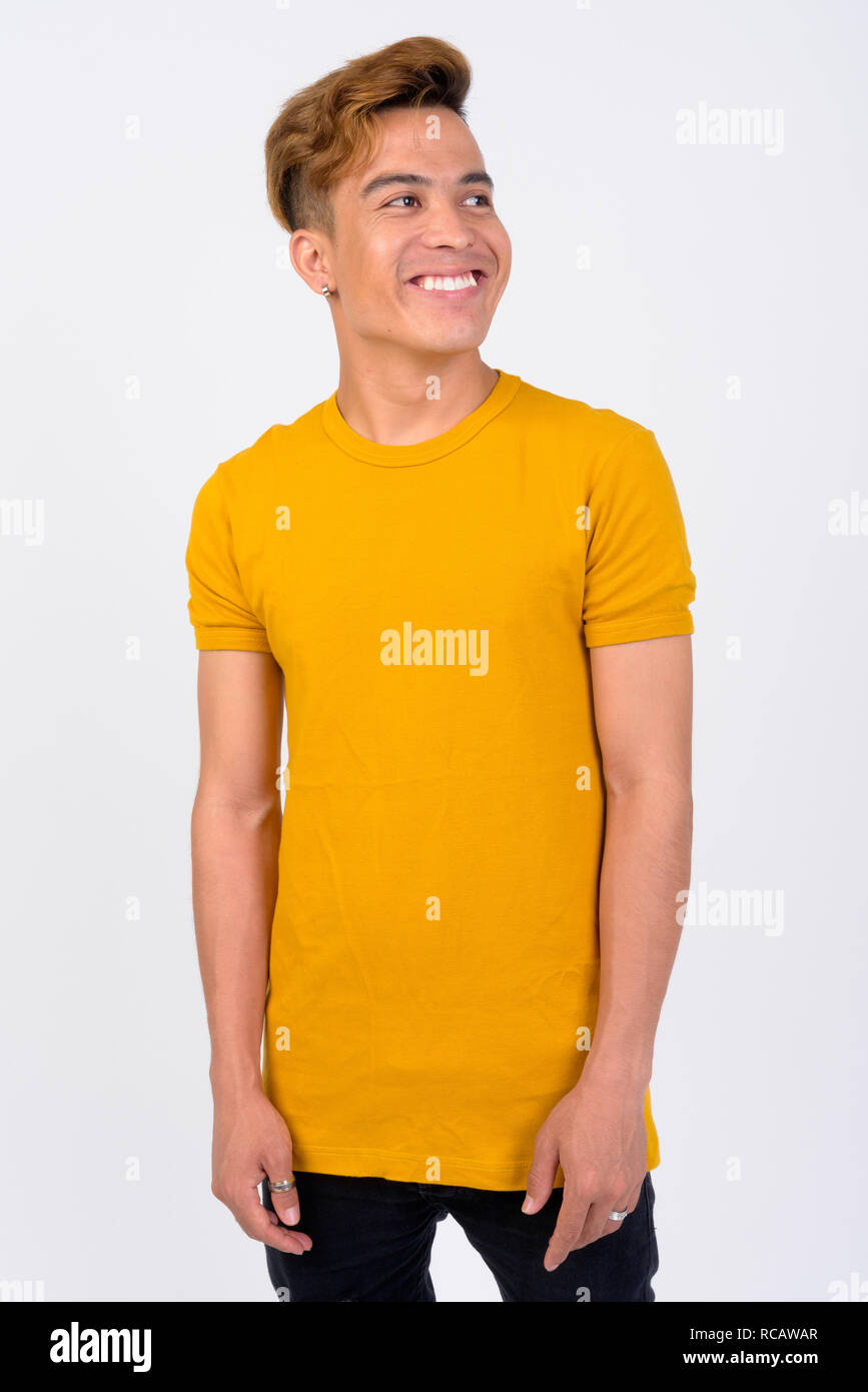 Portrait of happy young Asian man thinking against white background ...