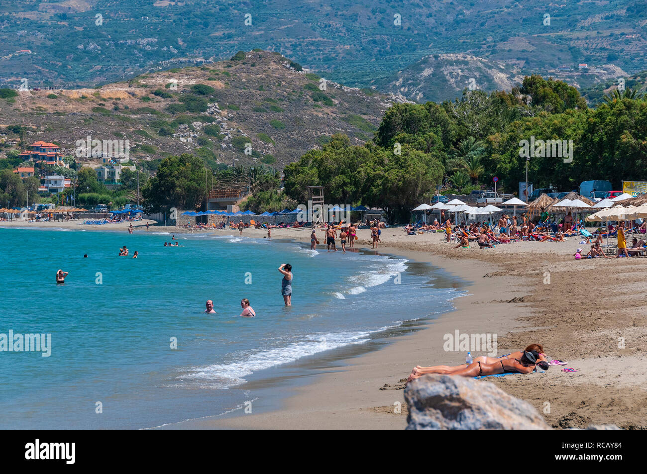 Tourist and locals enjoying the beach on a hot day in summer at Sitia ...