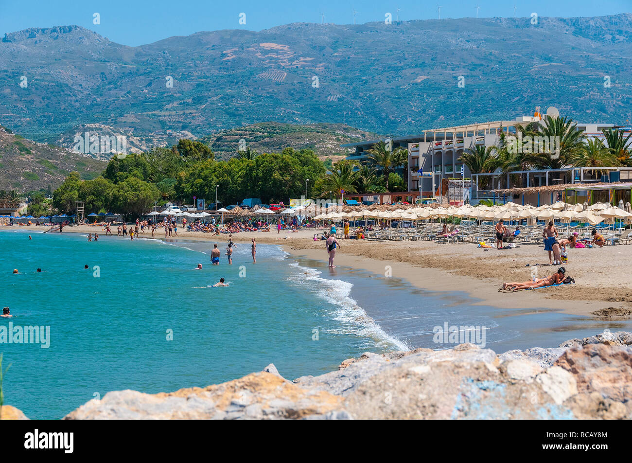 Tourist and locals enjoying the beach on a hot day in summer at Sitia ...