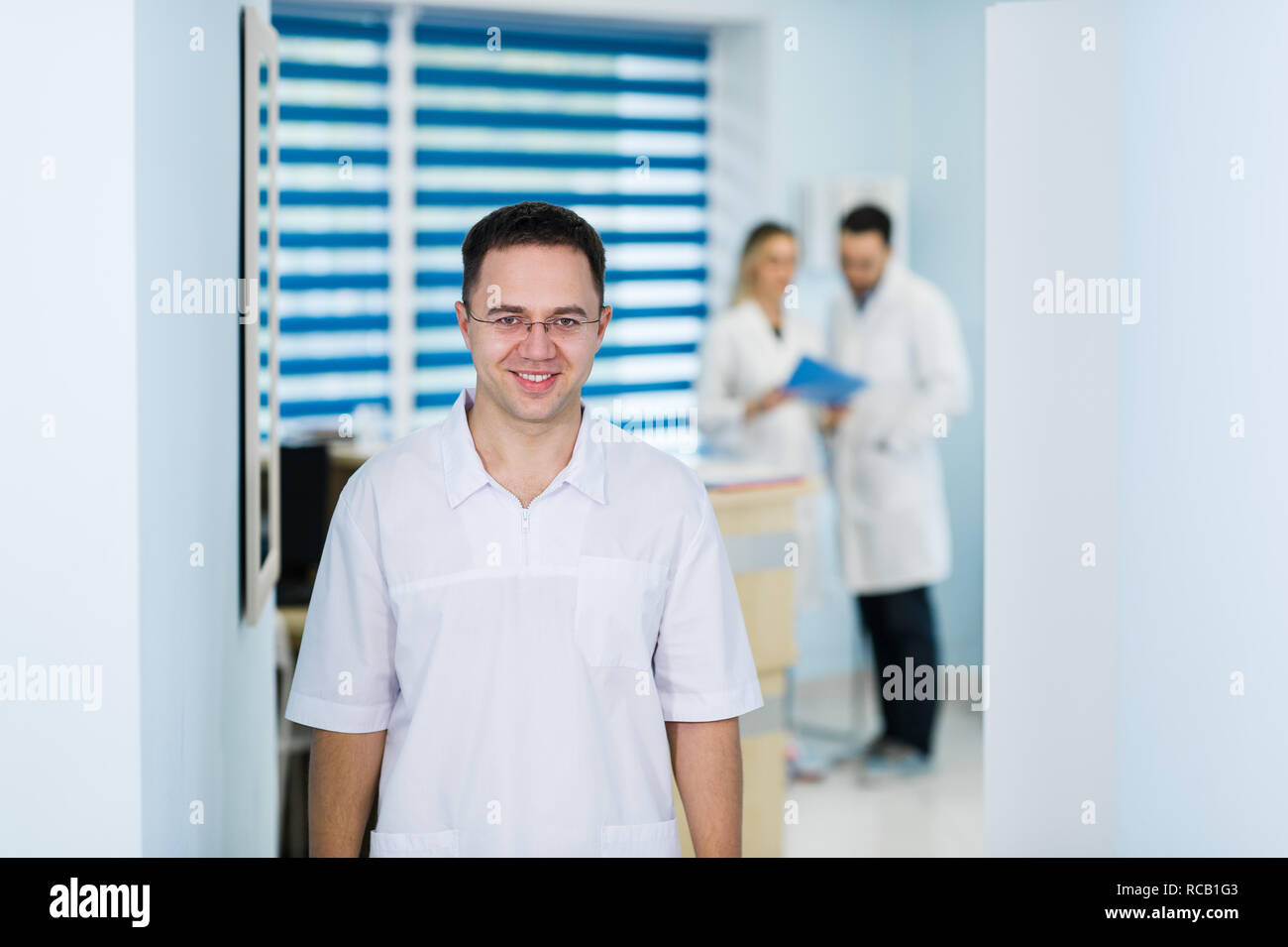 Doctor looking at camera while his colleague discussing in medical ...