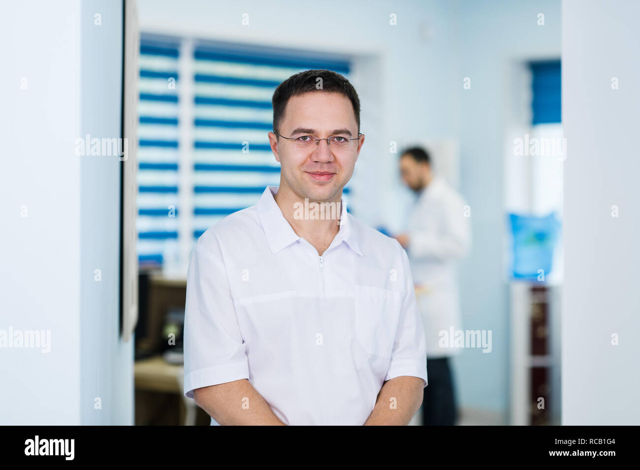 Doctor looking at camera while his colleague discussing in medical ...
