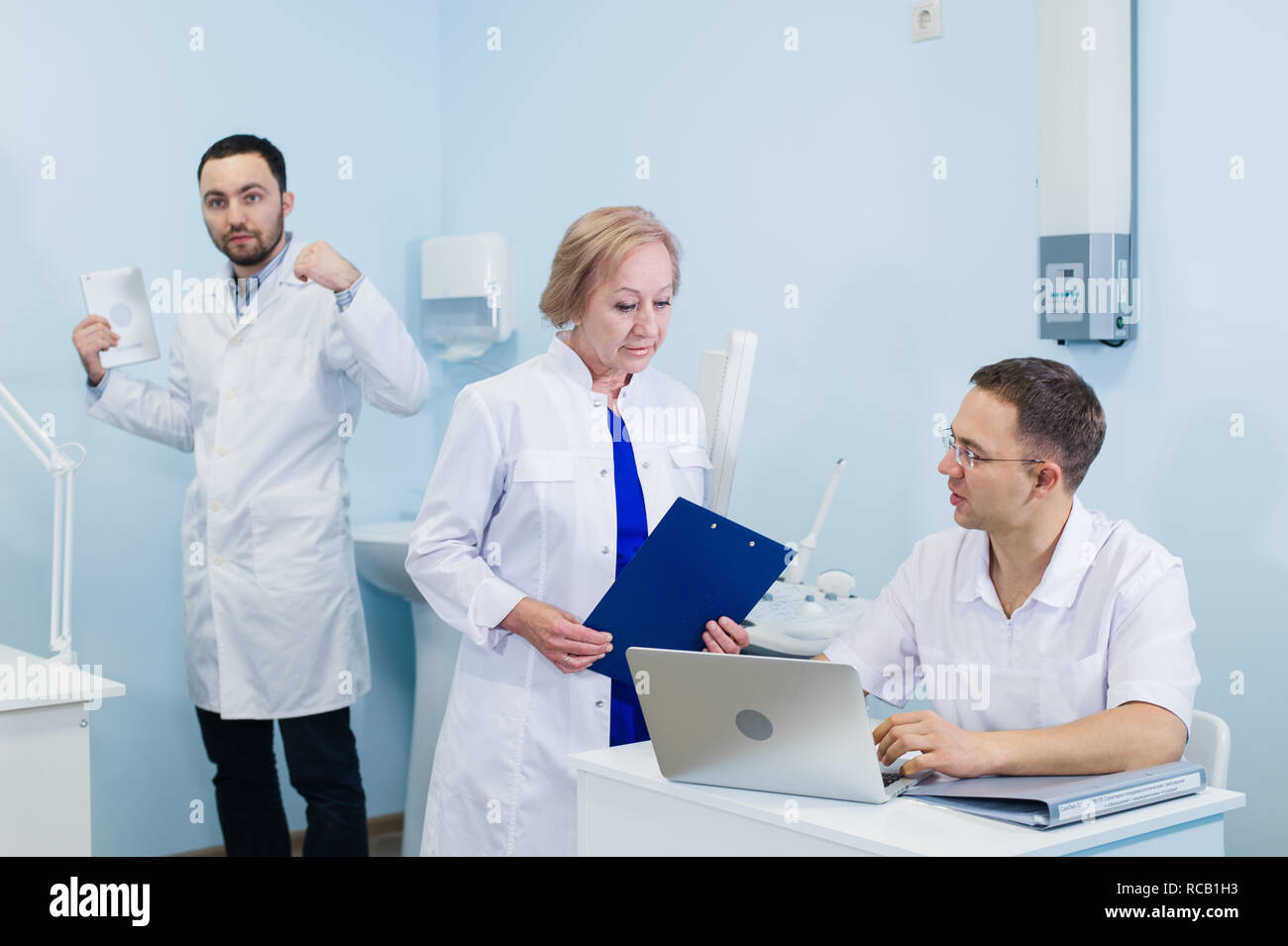 Beautiful mature serious doctors are using a laptop, discussing ...