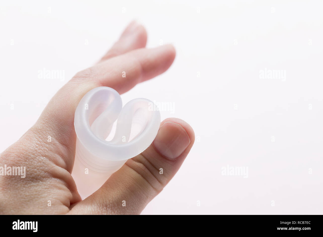Close up of woman hand folding menstrual cup showing how to use, c form ...