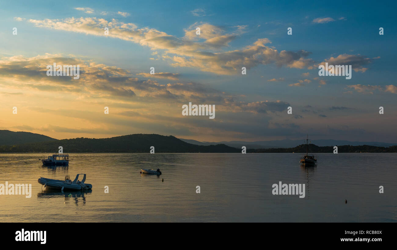 Calm colorful sunset over a picturesque bay area near boat and yacht ...