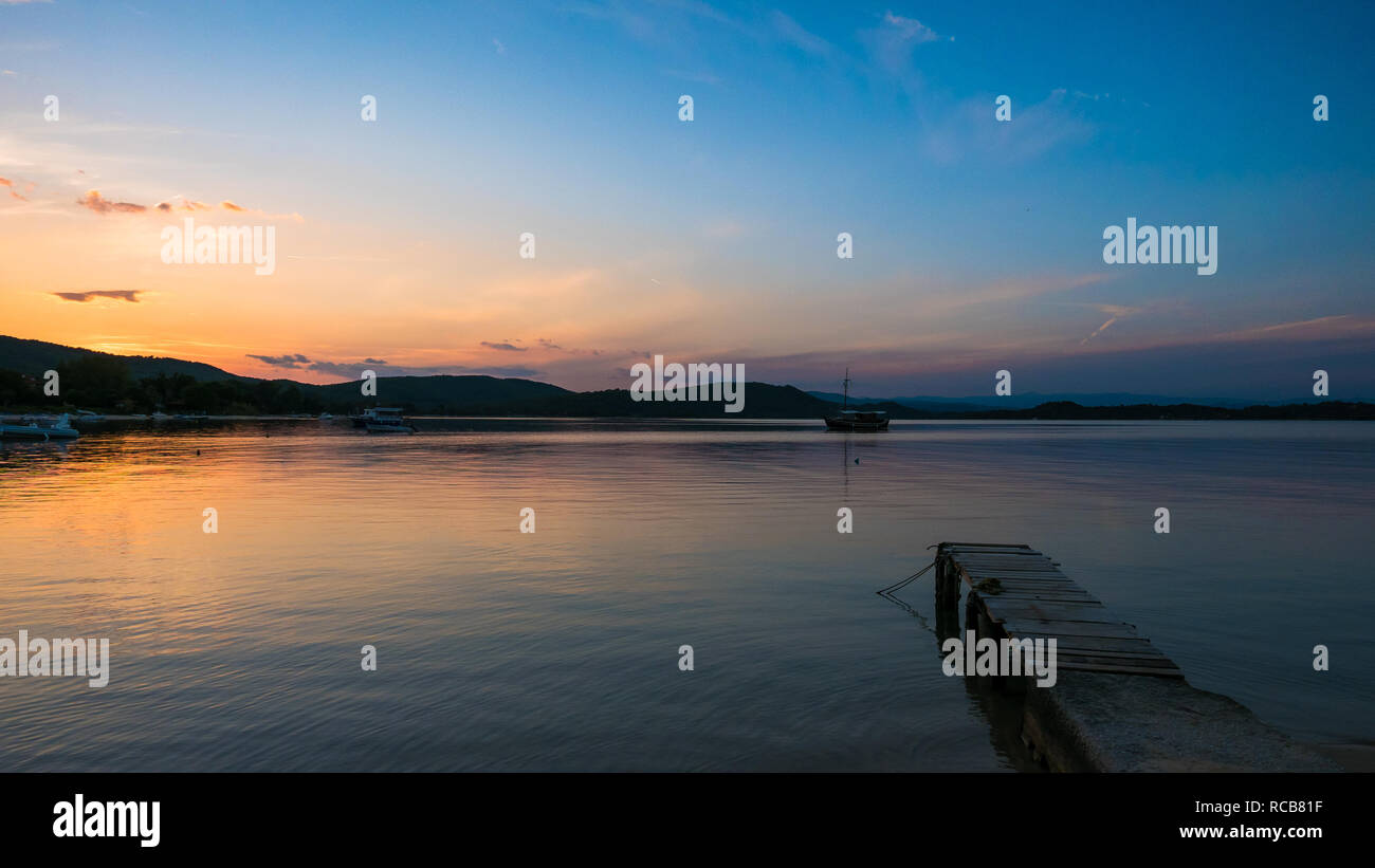 Calm colorful sunset over a picturesque bay area near boat and yacht ...
