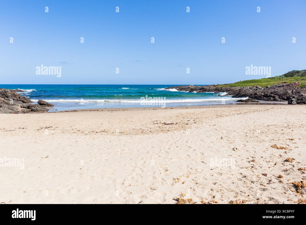 Beach cove with blue ocean wave waters to horizon with rocky coastline ...