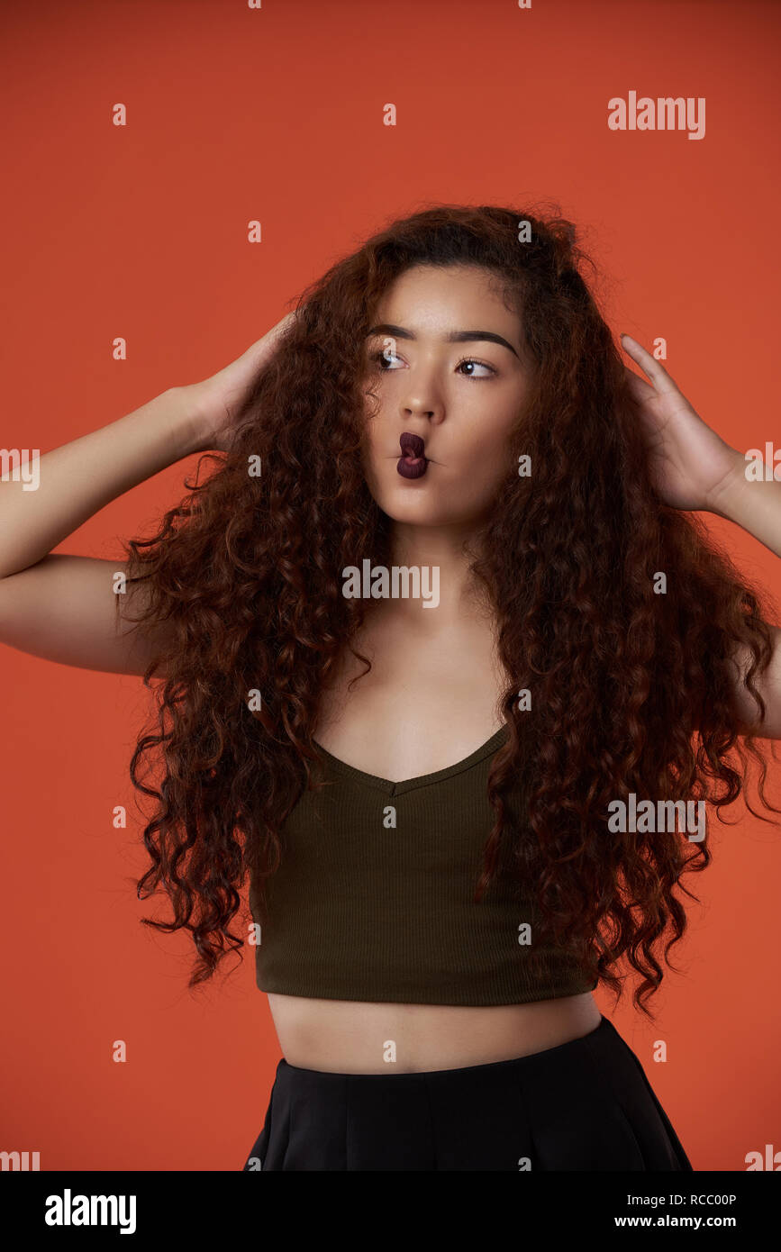 Young girl showing fish face on orange color studio background Stock ...