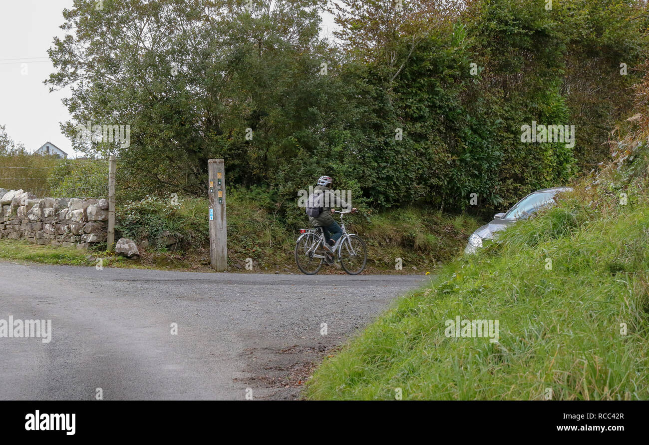Cyclist crossing road at intersection on the Great Western Greenway, a ...
