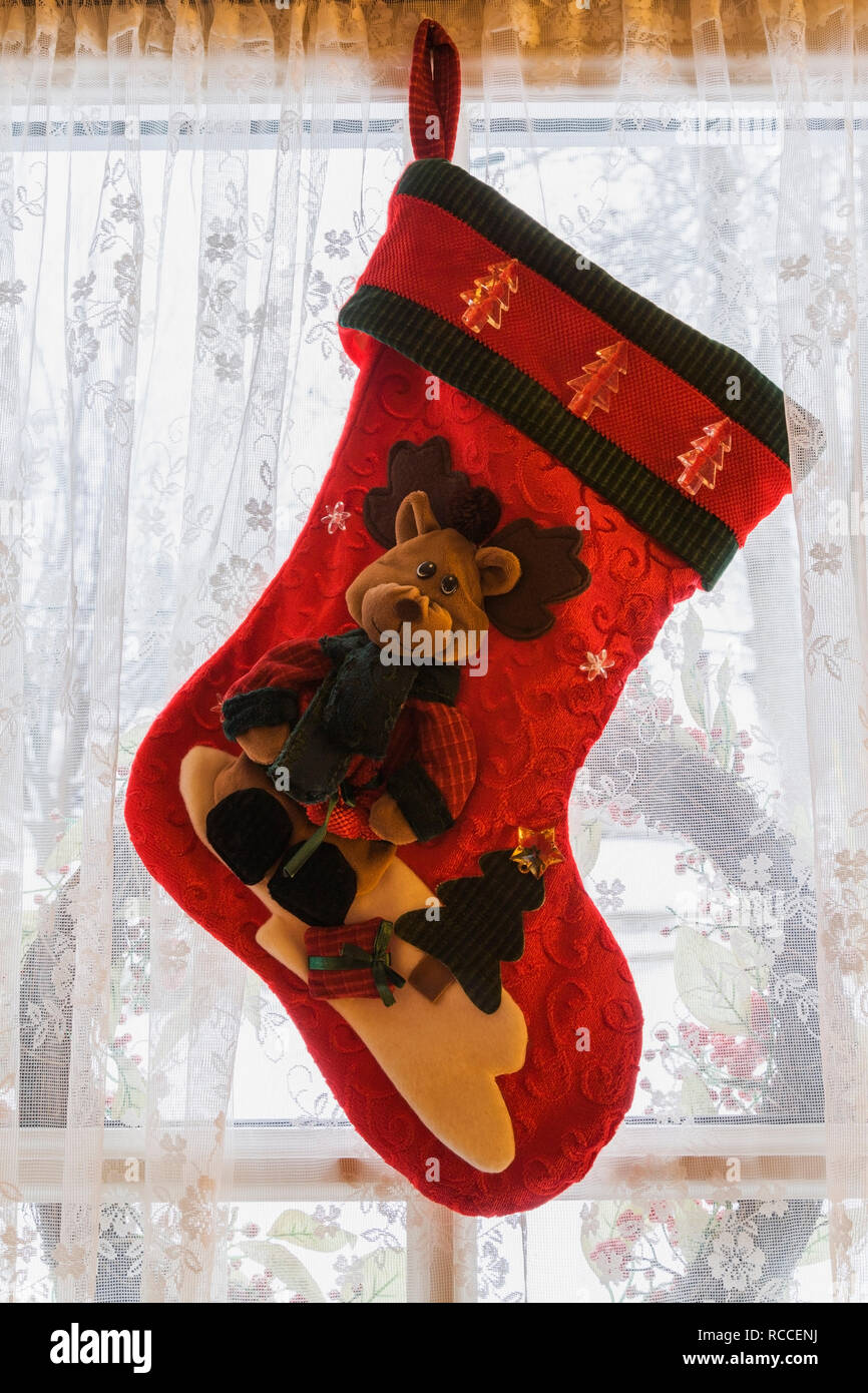 Red Christmas stocking decorated with brown teddy bear hung on a window ...