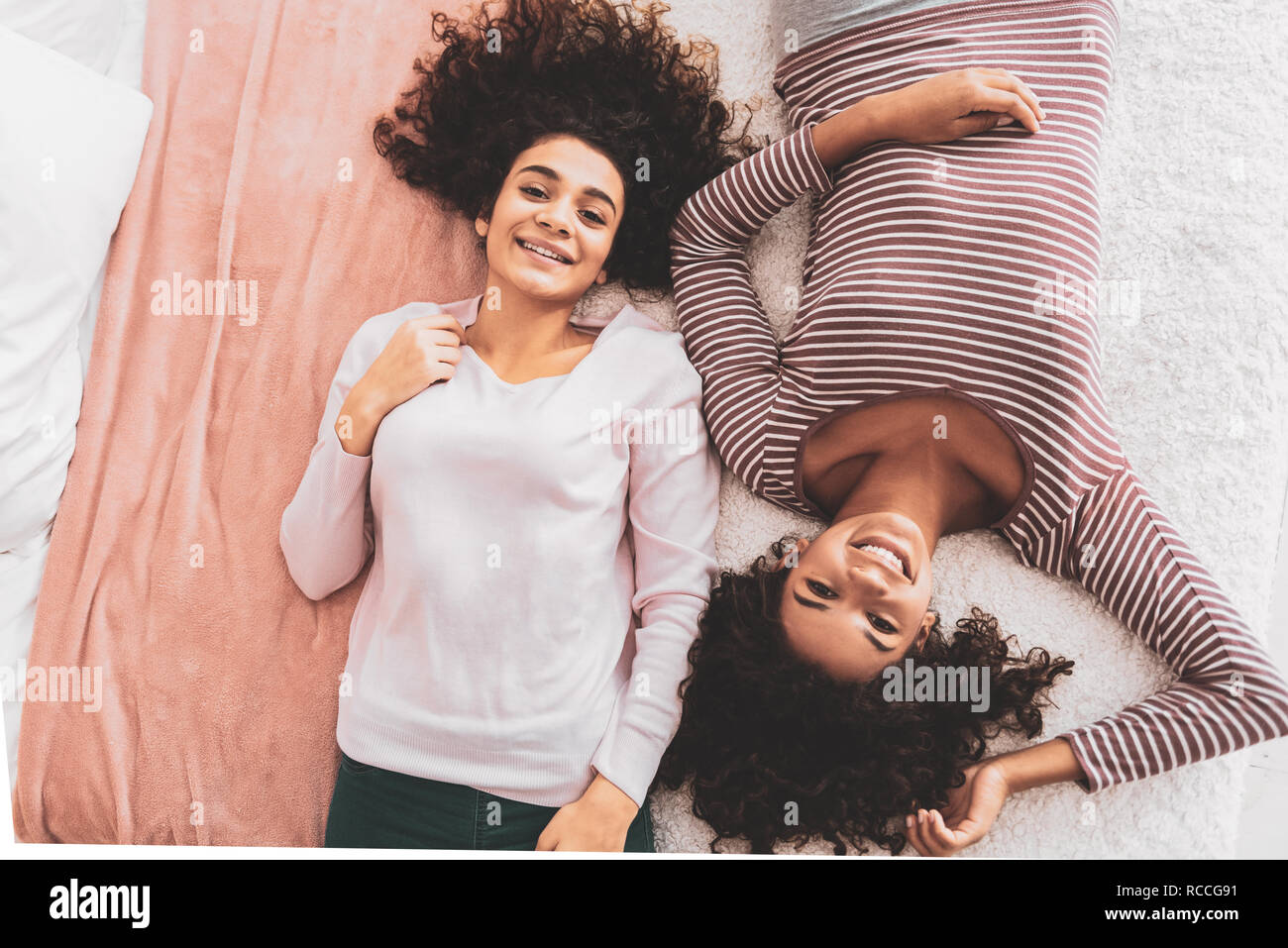 Smiling good-looking friends lying on double bed Stock Photo - Alamy