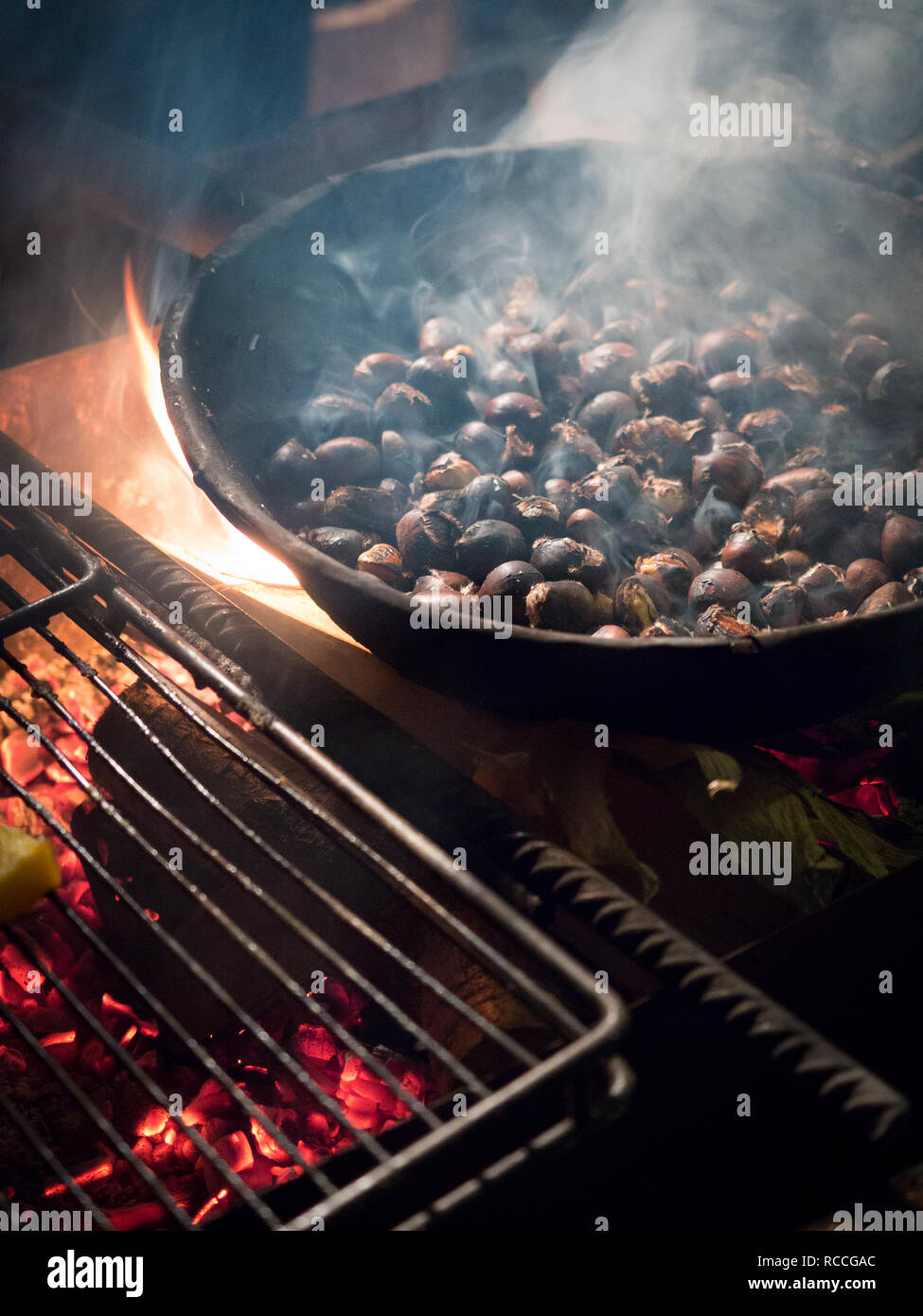 Pan-fried chestnuts cooked directly on the flame of an outdoor fire ...