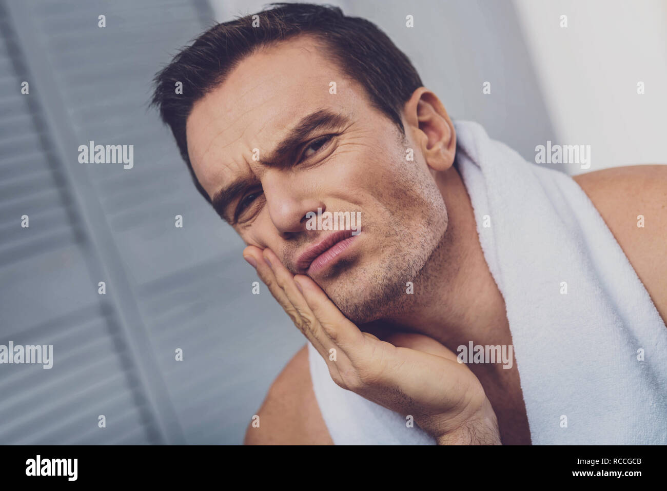 Sad unhappy man holding his cheek Stock Photo - Alamy