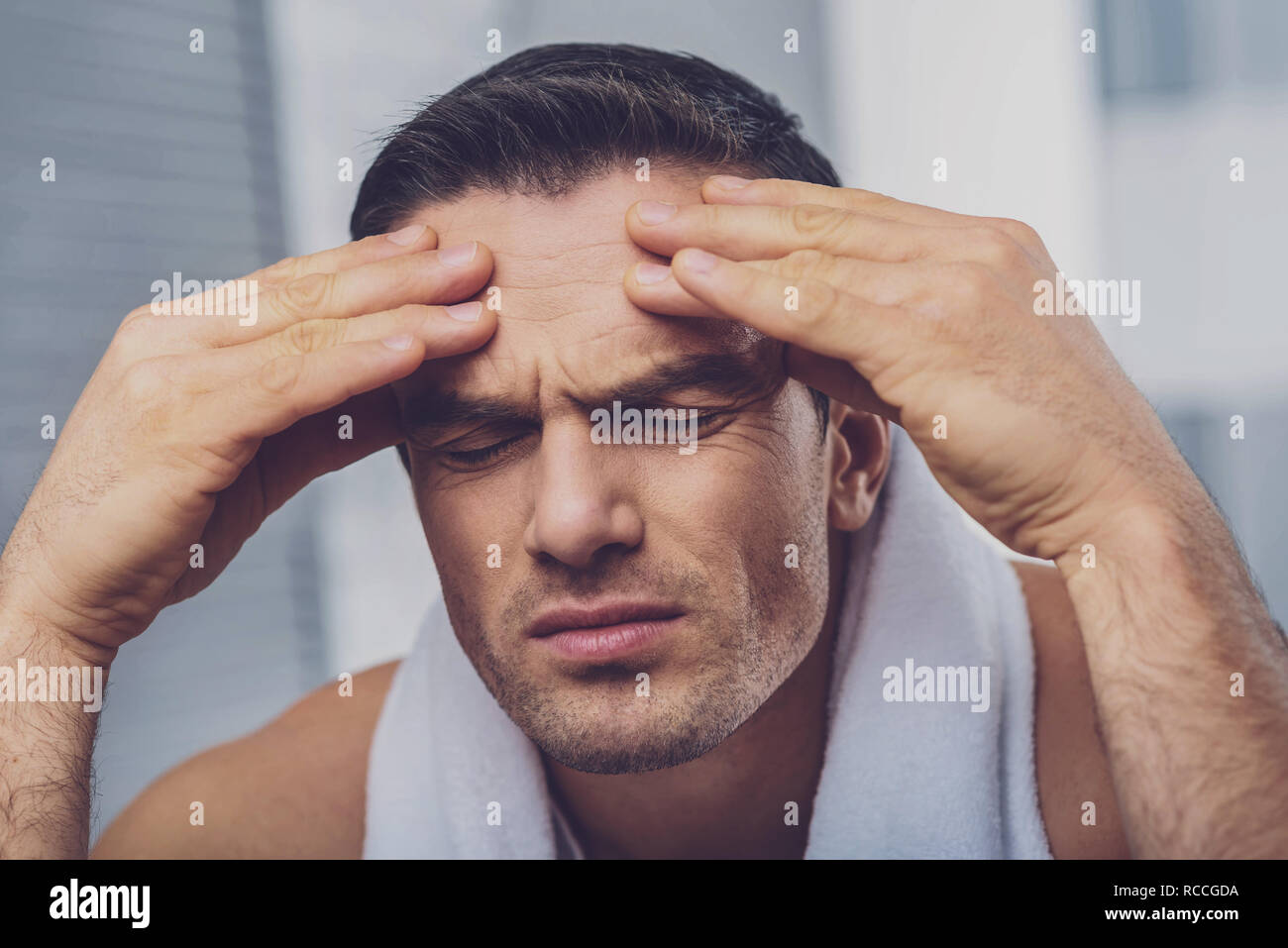 Sad cheerless man holding his forehead Stock Photo - Alamy