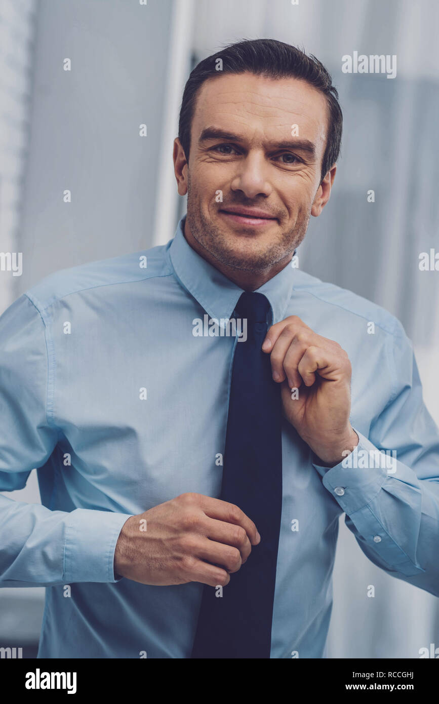 Joyful positive man holding his tie Stock Photo - Alamy Joyful positive man holding his tie Stock Photo - Alamy
