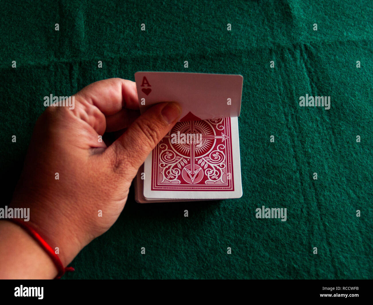 A person playing poker by raising the first card in the deck Stock ...