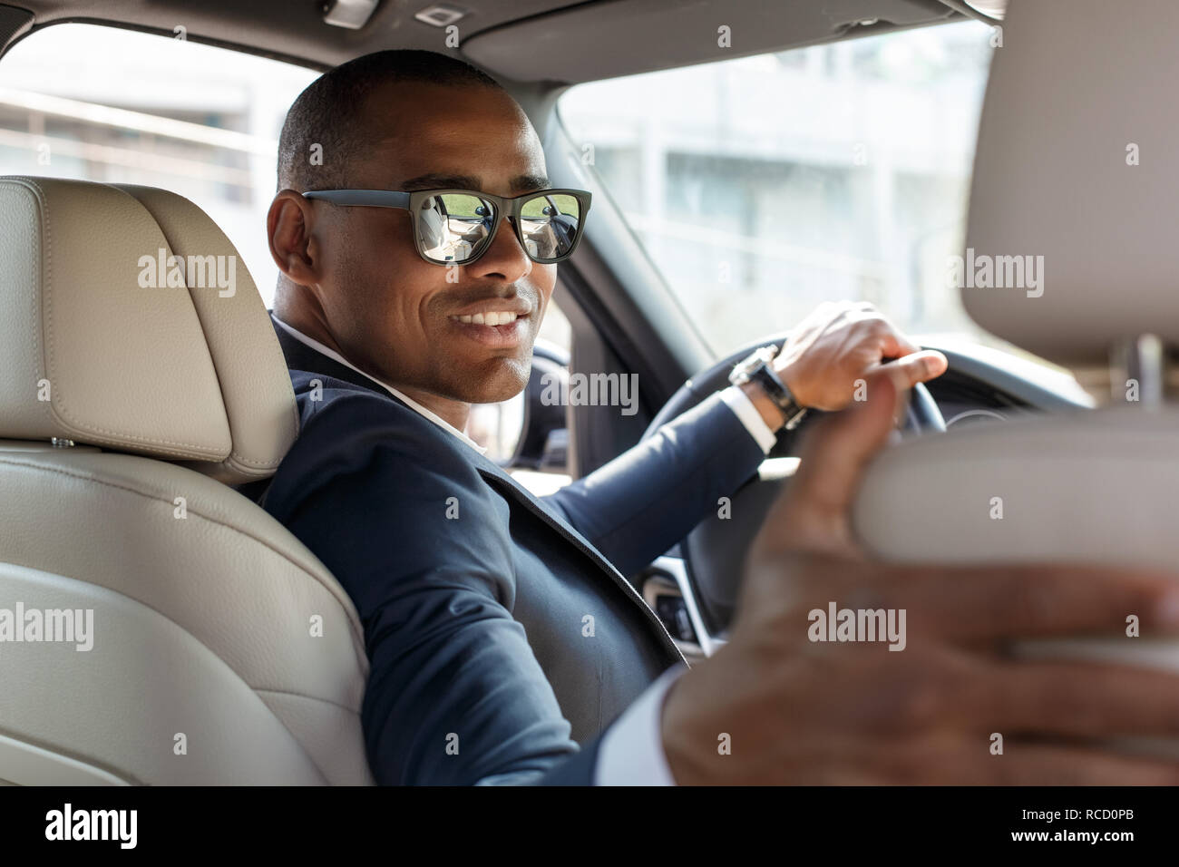 Young mulatto businessman driver wearing sunglasses sitting inside the ...
