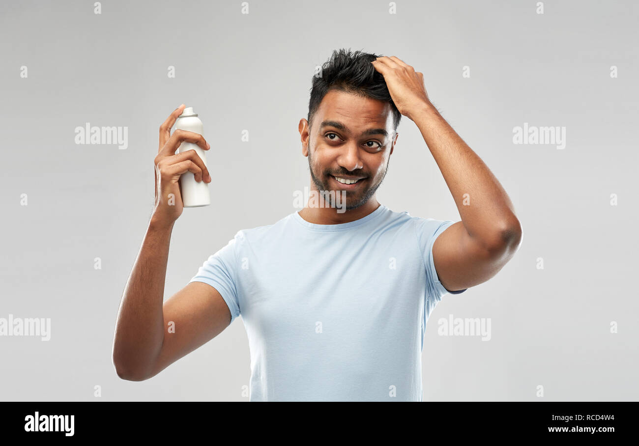 smiling indian man applying hair spray over gray Stock Photo - Alamy