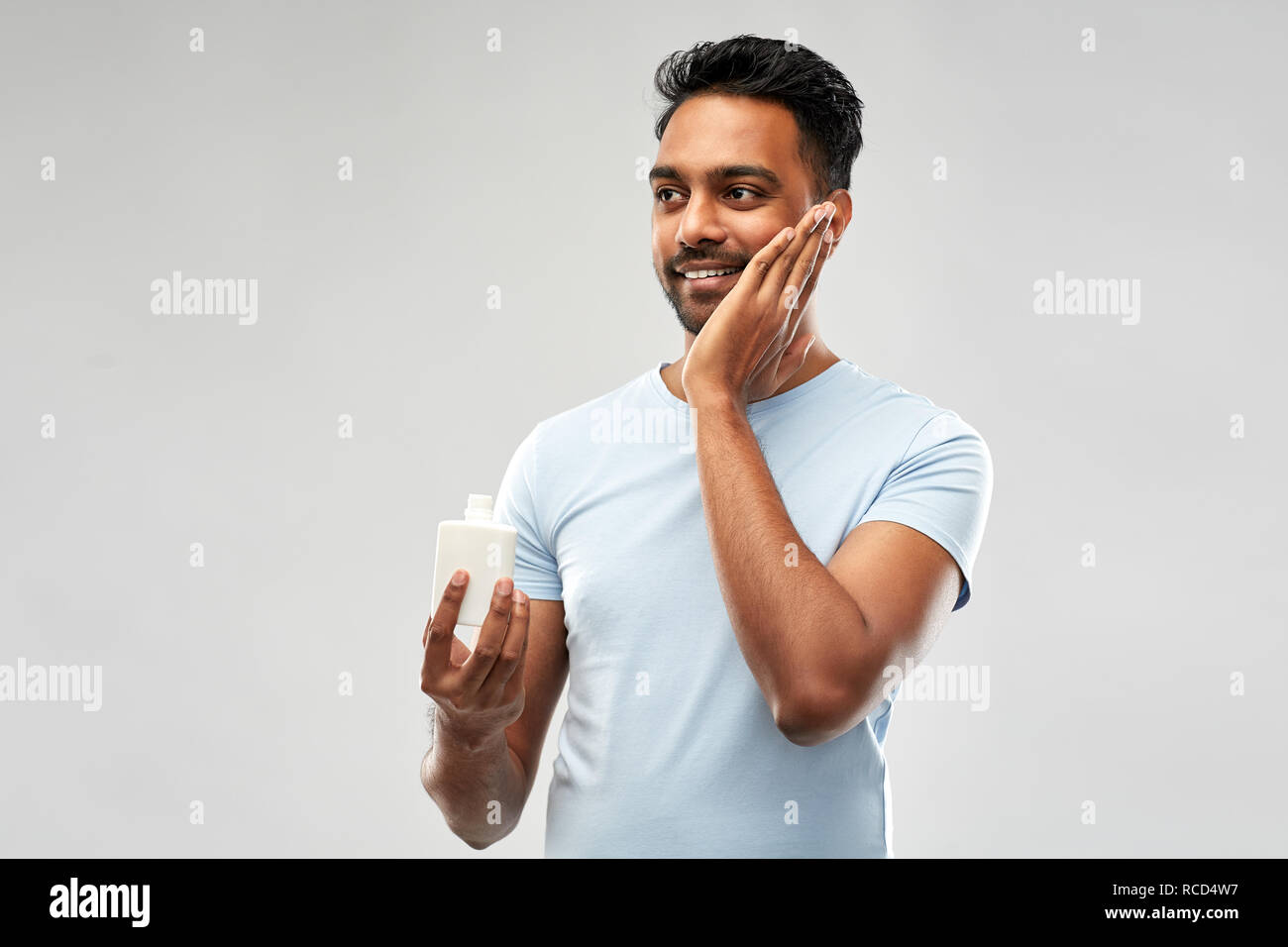 happy indian man applying lotion to face Stock Photo - Alamy