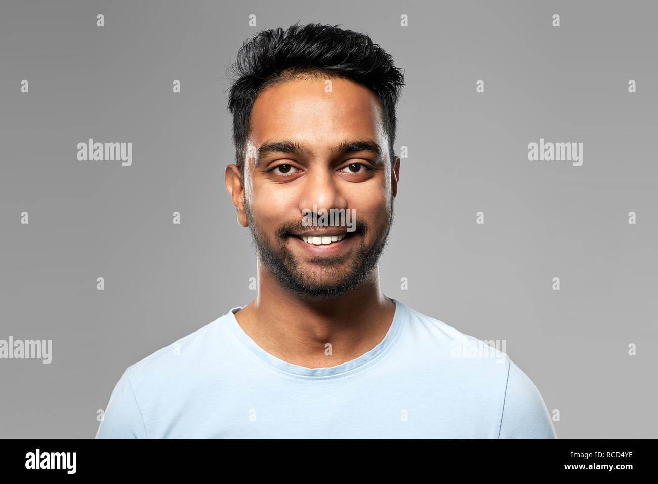 smiling young indian man over grey background Stock Photo - Alamy