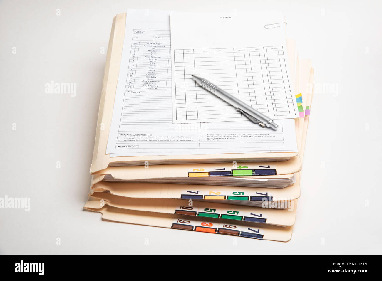 A stack of numbered and color coded medical records folders topped with ...