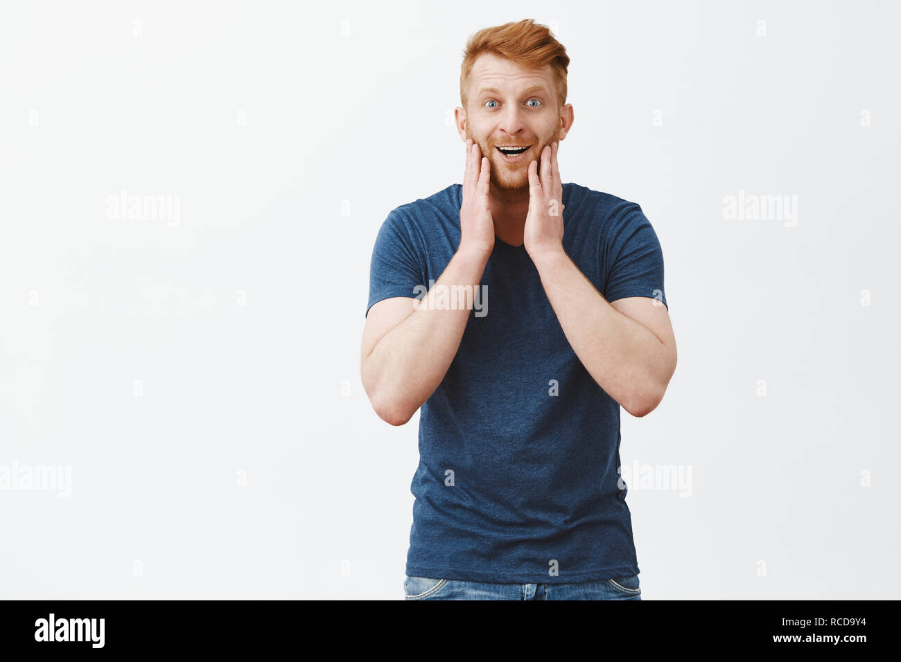 Pleased and amazed guy looking in mirror, satisfied with new haircut ...