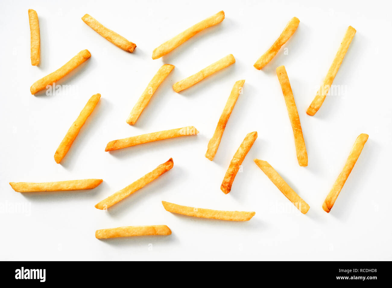 Scattered thin straight fried potato chips on a white background viewed ...