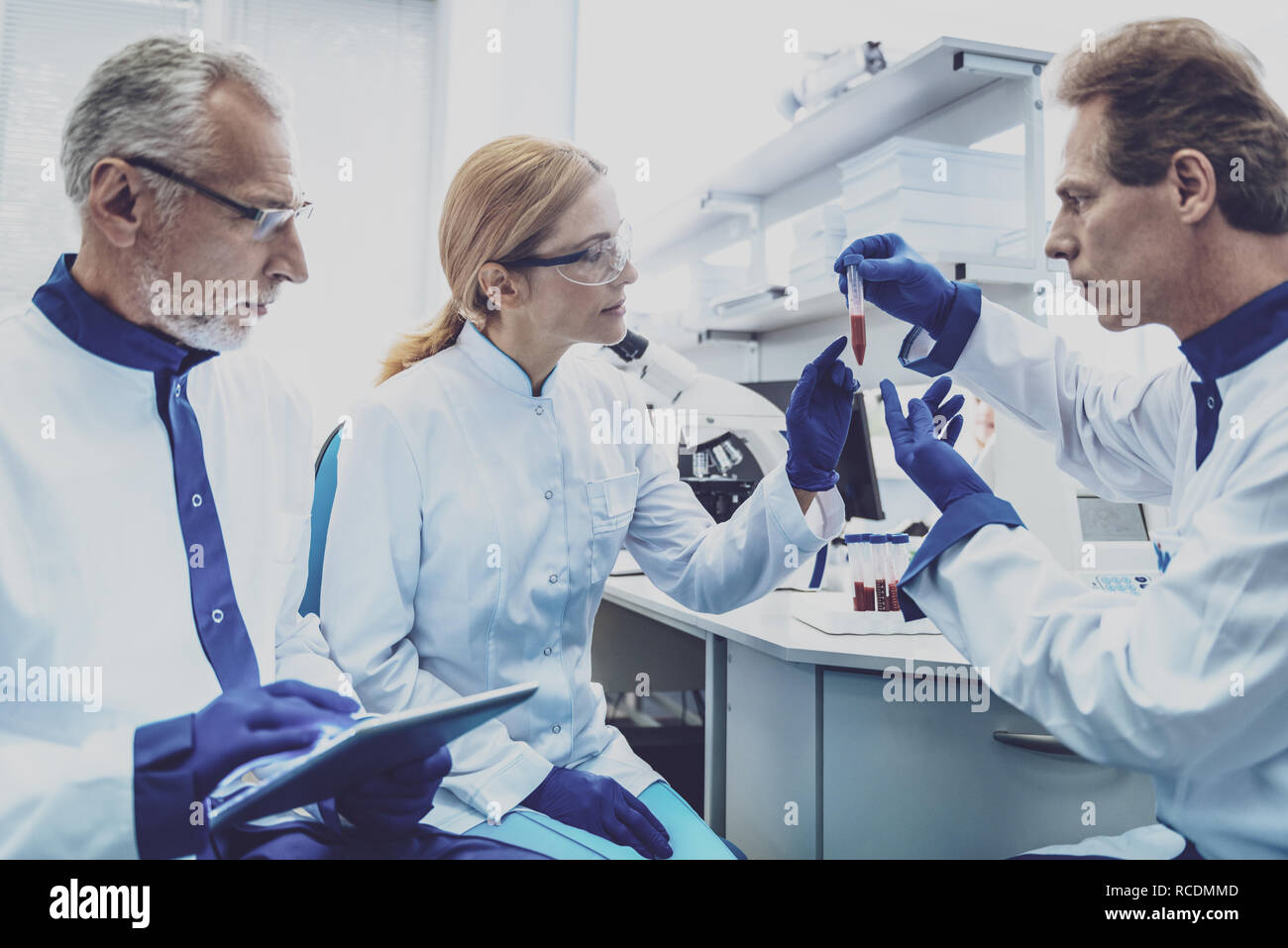 Serious lab assistant demonstrating test tube Stock Photo - Alamy