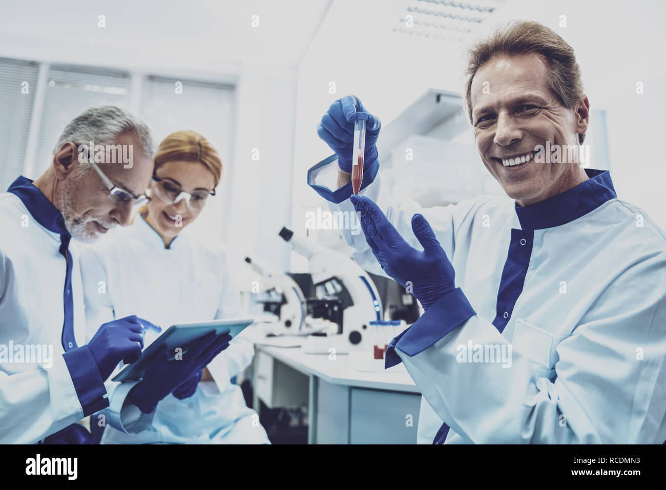 Happy researcher demonstrating test tube Stock Photo - Alamy