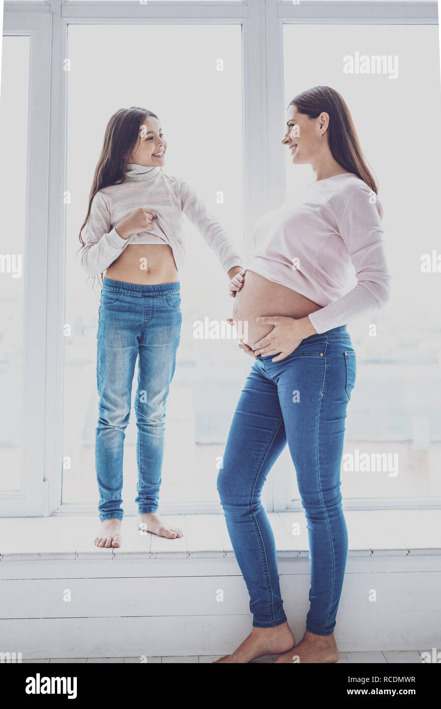 Upbeat little girl touching her pregnant mums belly Stock Photo - Alamy