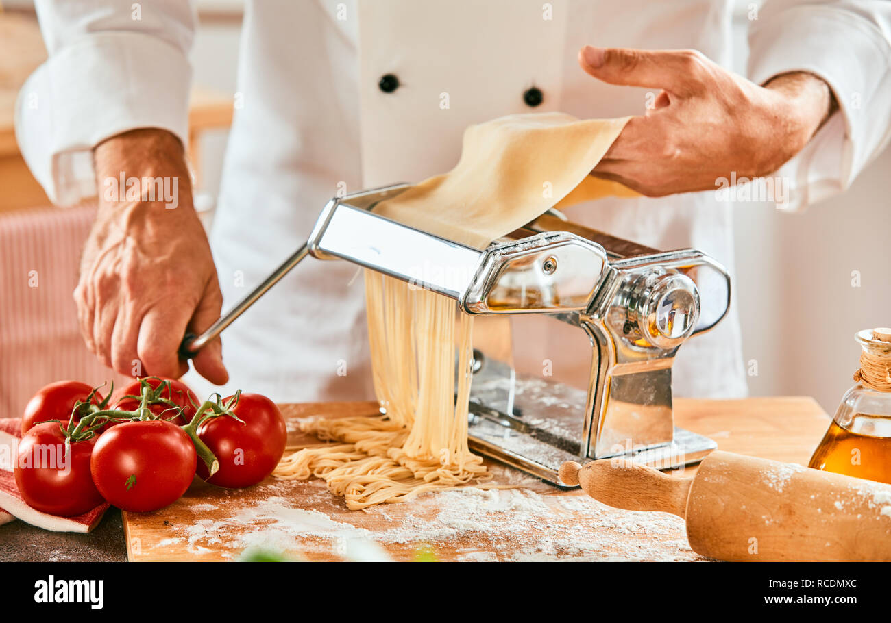 Italian chef making homemade spaghetti pasta using a cutting machine ...