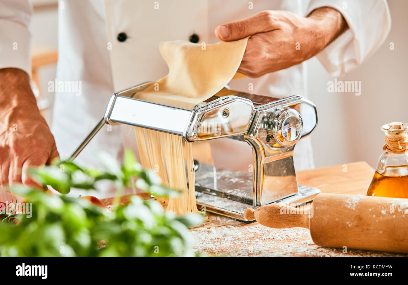 Italian chef preparing homemade spaghetti pasta using a cutting machine ...