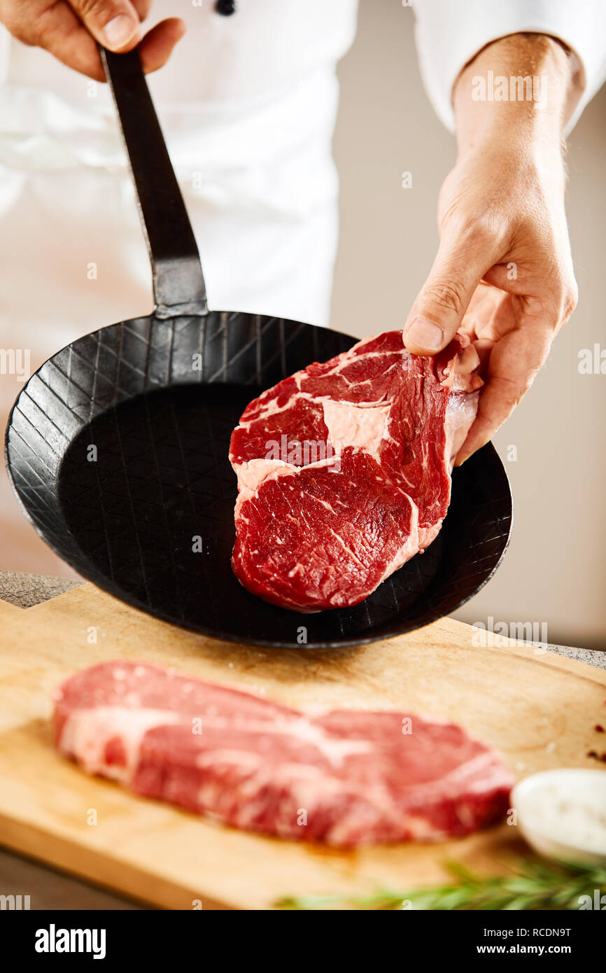 Chef holding a slab of fresh raw beef steak with marbled fat over an ...
