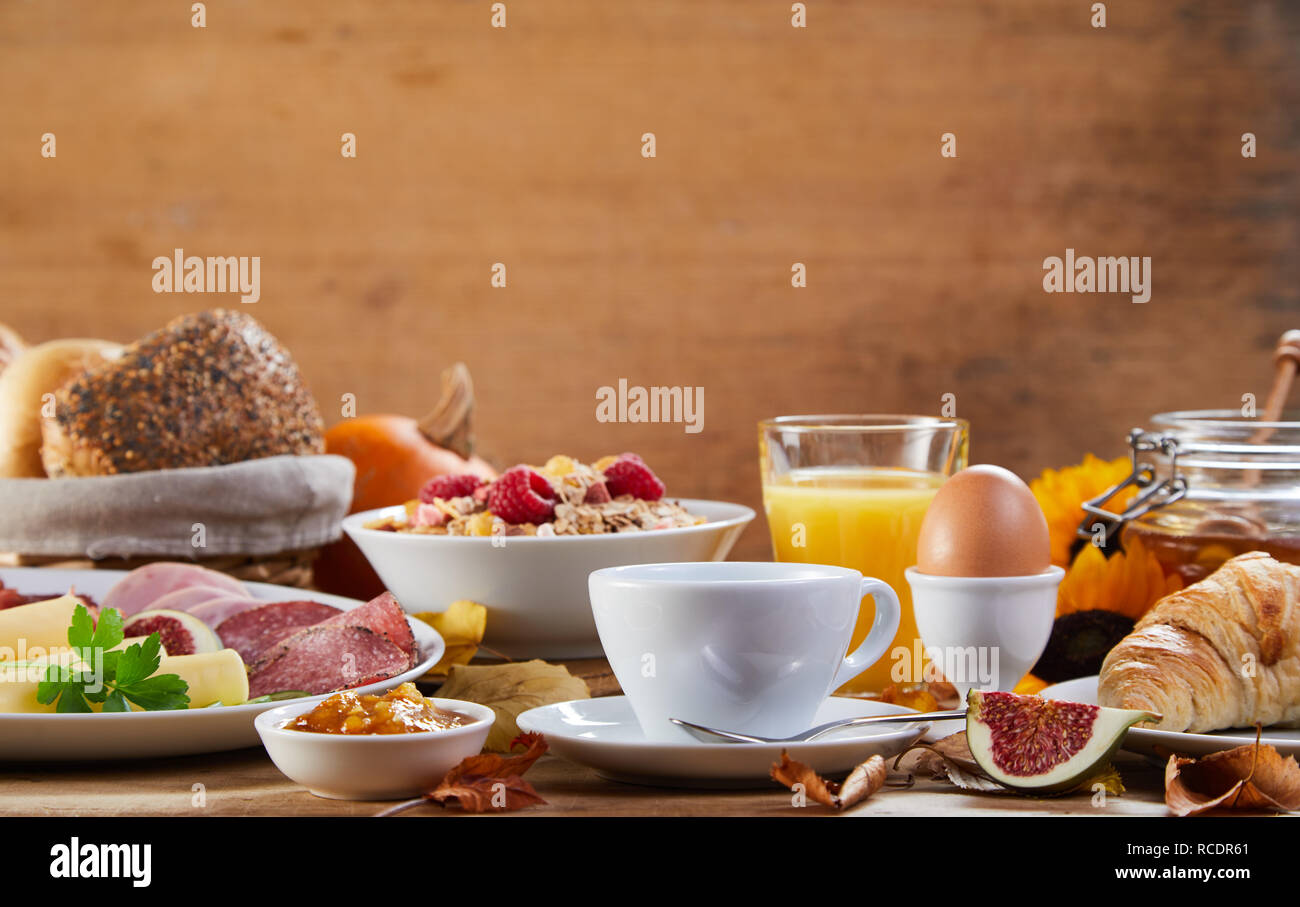 Side view of table with breakfast meal and snacks, cup of coffee, juice ...
