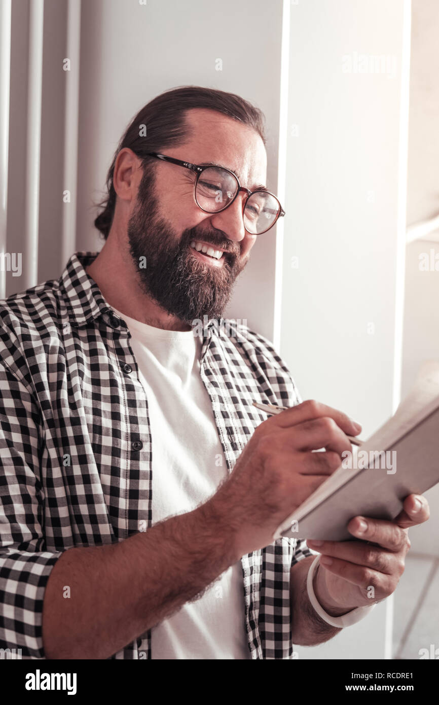 Smiling man drawing a sketch in his notebook Stock Photo - Alamy
