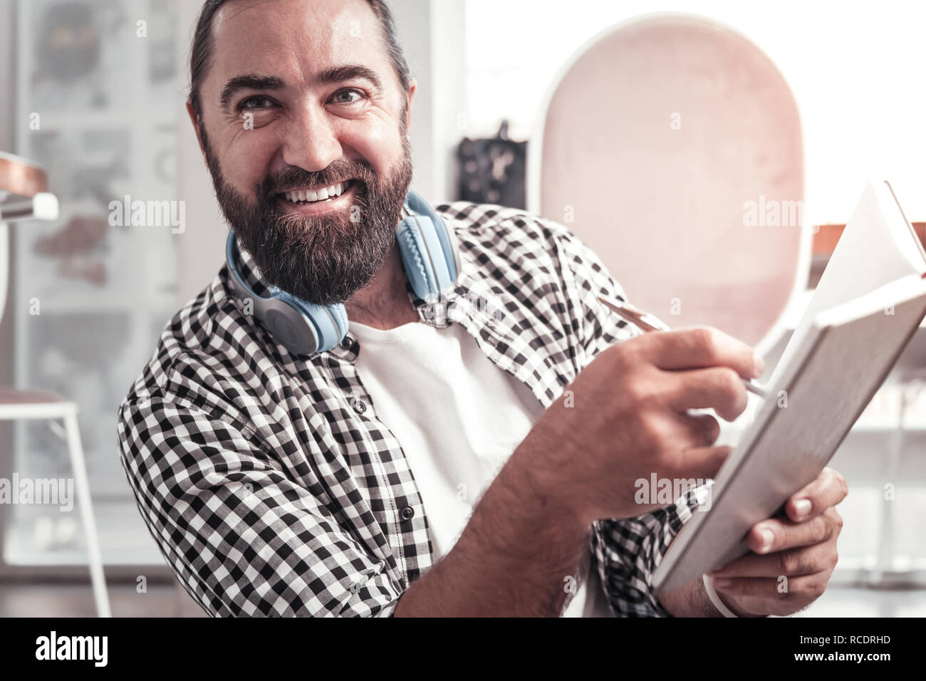 Smiling man holding his notebook while working Stock Photo - Alamy