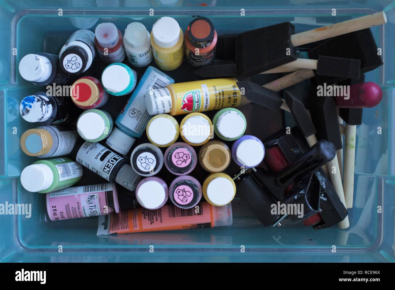 A plastic container full of acrylic paints, foam brushes, and rollers ...