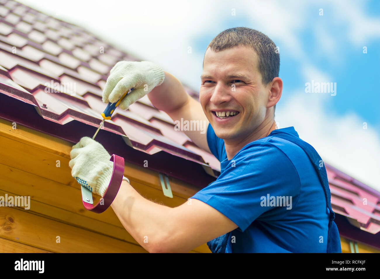 Happy man is repairing the roof of the house, a portrait on the ...