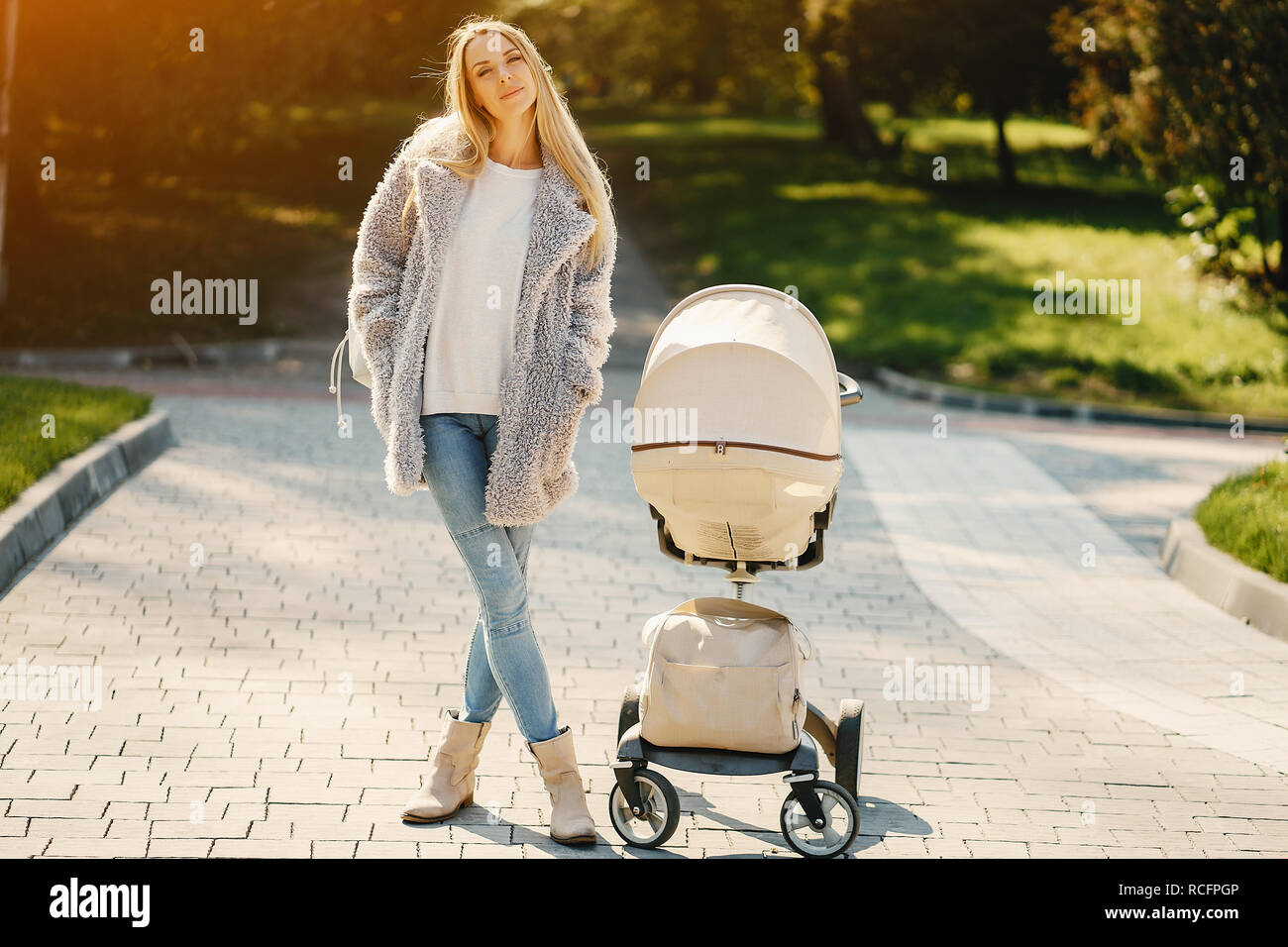stylish young blonde mother pushing stroller Stock Photo - Alamy