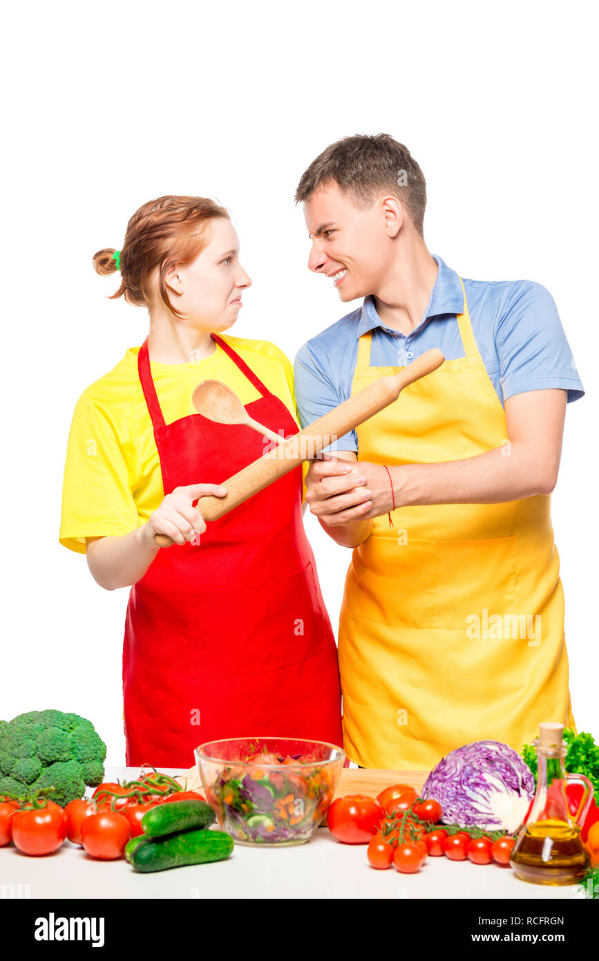 couple fighting with kitchen utensils while cooking salad on white ...