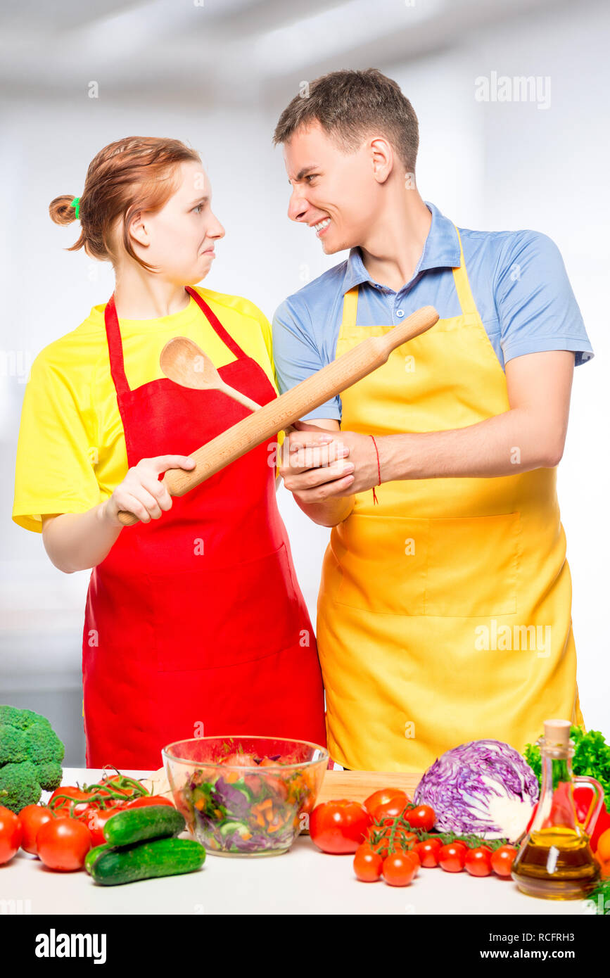 couple fighting kitchen utensils while cooking salad in the kitchen ...