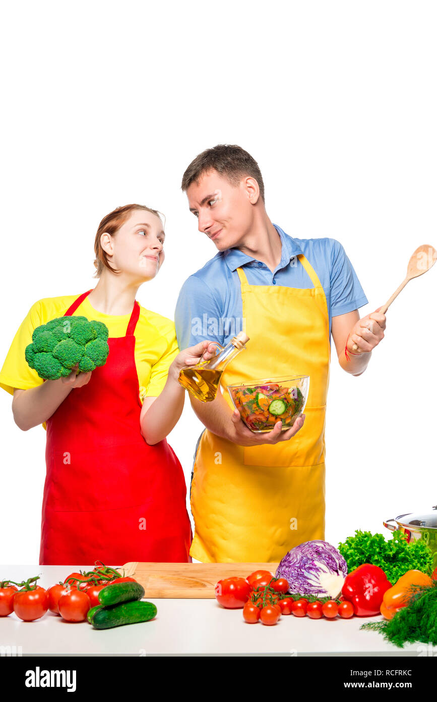 A young couple looks at each other in love while cooking vegetable ...
