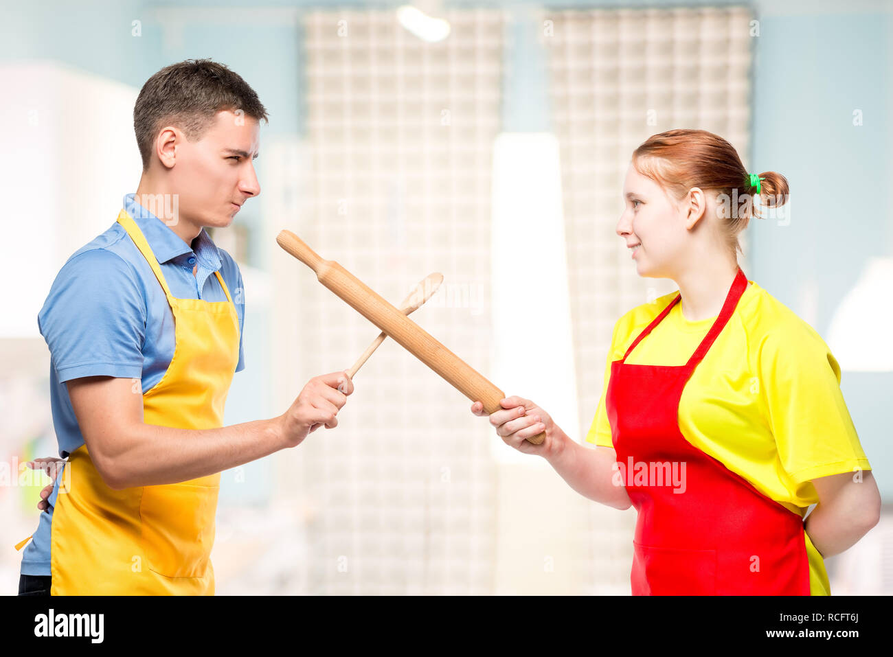 man and woman in an apron with kitchen utensils fighting in the kitchen ...