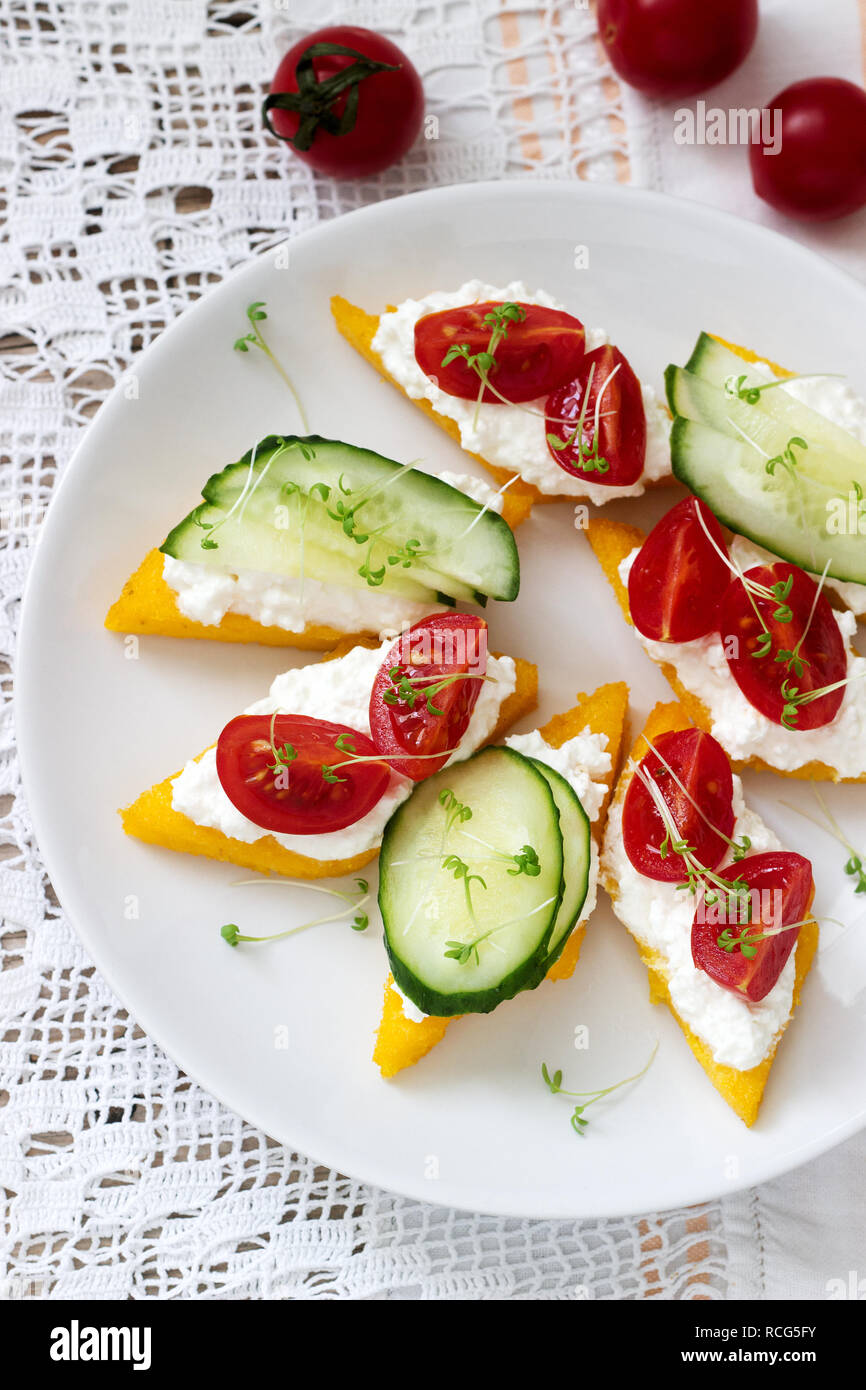 Vegetarian canapes from polenta with cheese, vegetables and cress on a ...