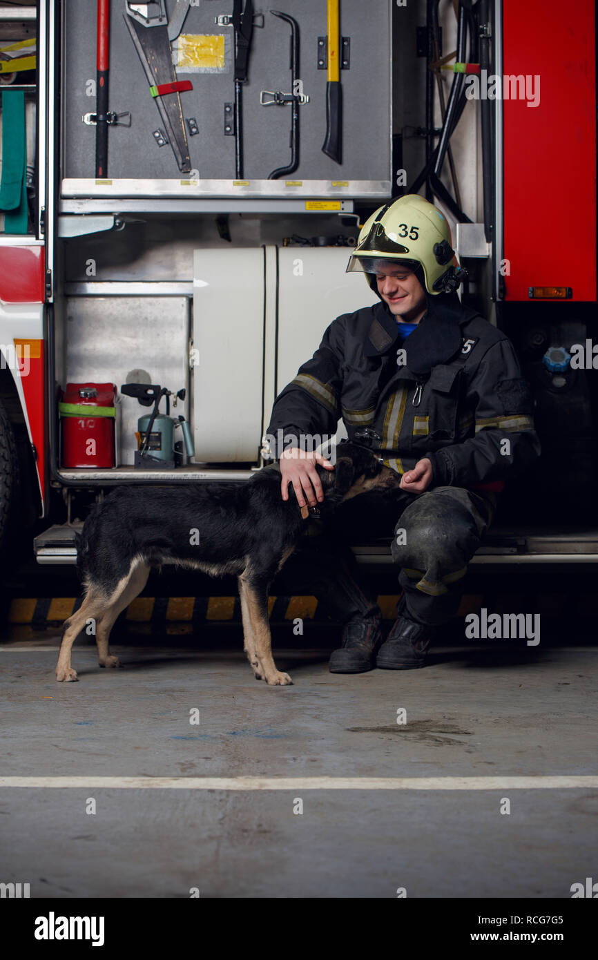 Photo of happy fireman in helmet with dog Stock Photo - Alamy