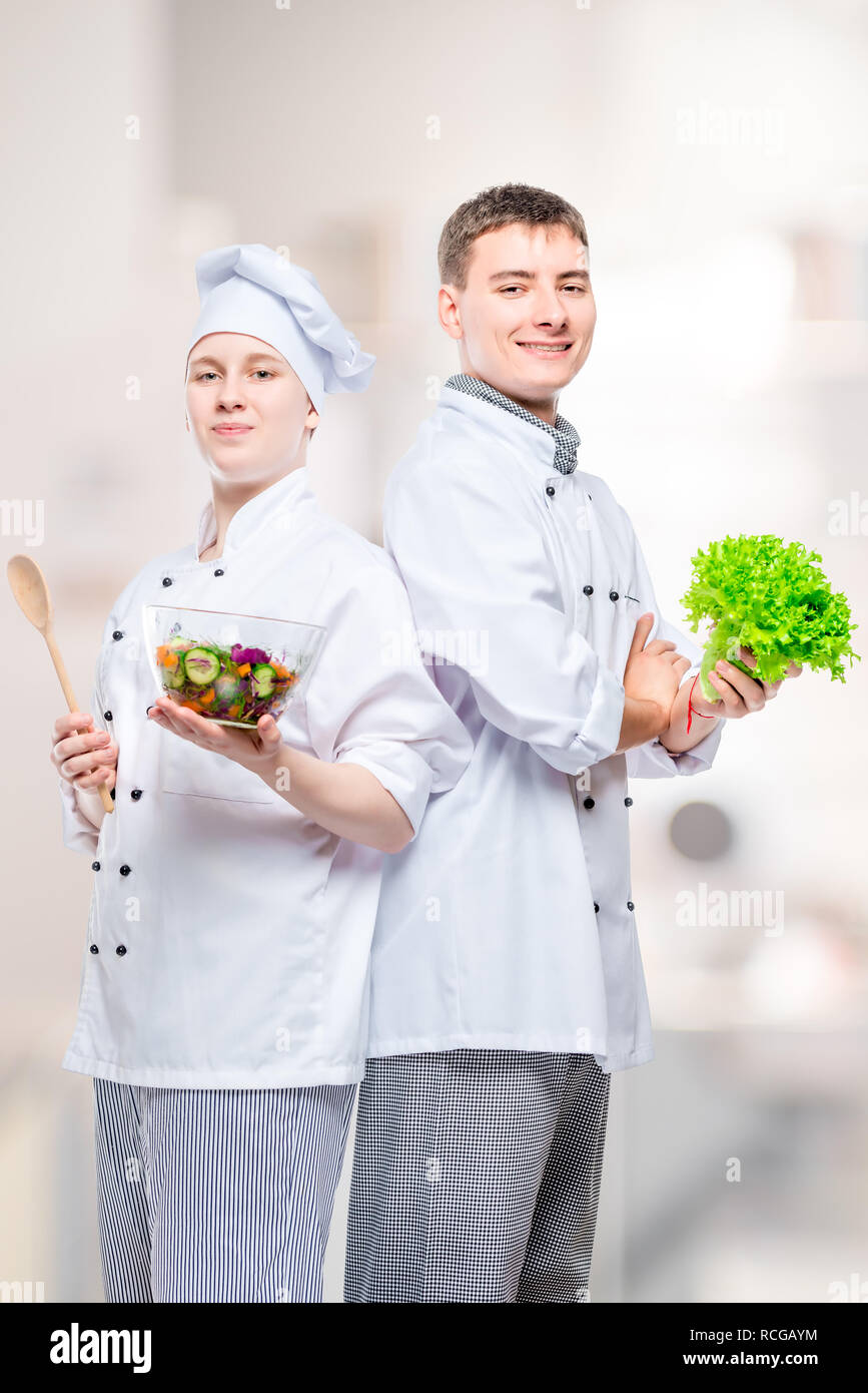 professional happy chefs in suits with a salad in their hands against ...