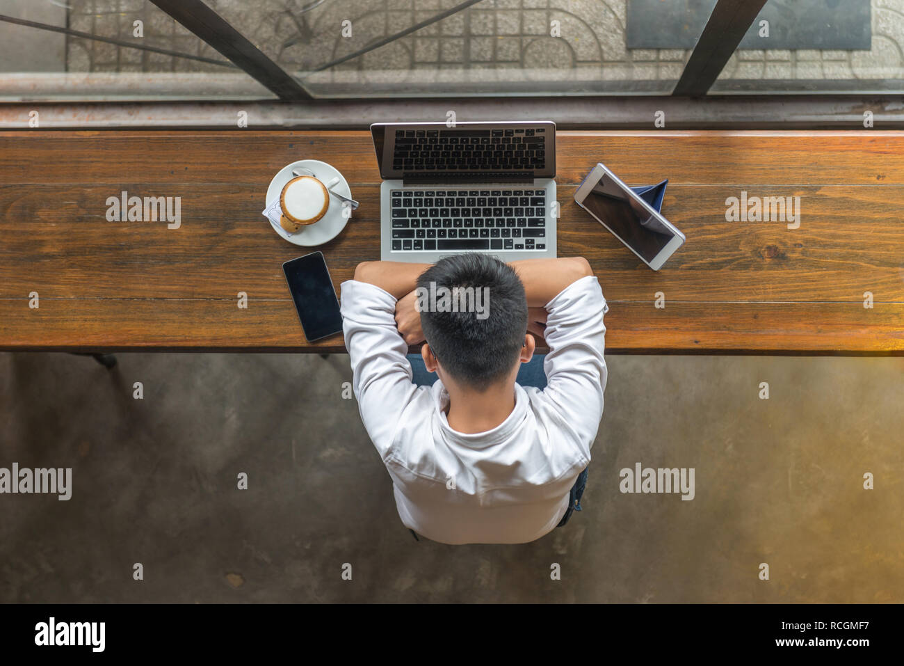 The man sleeping next to laptop, smartphone and tablet at cafeteria ...