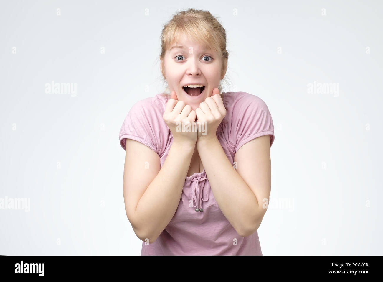 Young woman smiling very happy surprised holding hands near head being ...