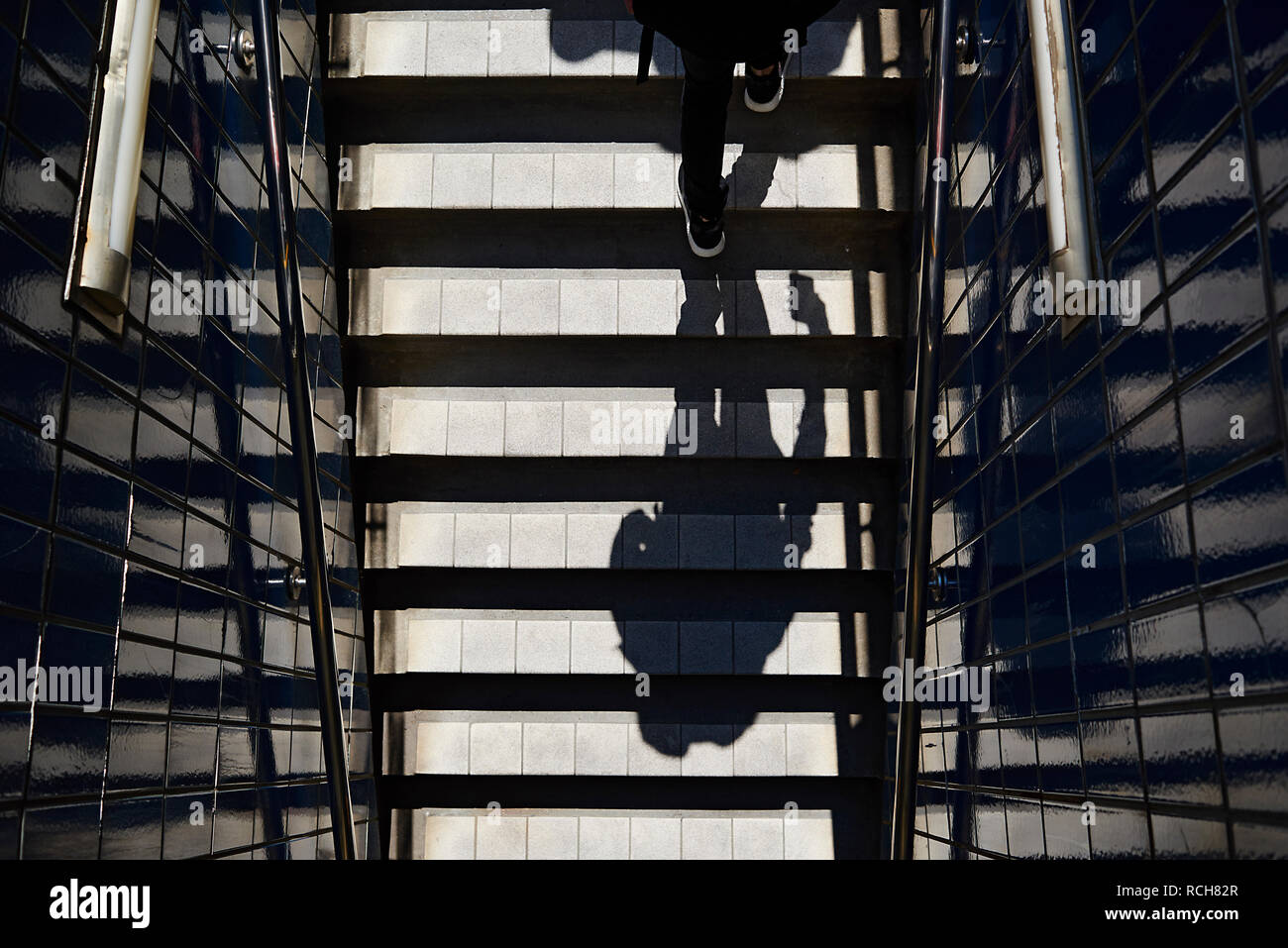 Top down shot of the shadow of a man walking down the stairs into the ...