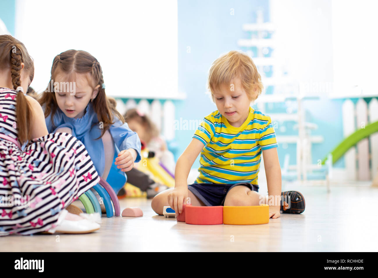 Children playing wooden toys at day care center, kindergarten or ...